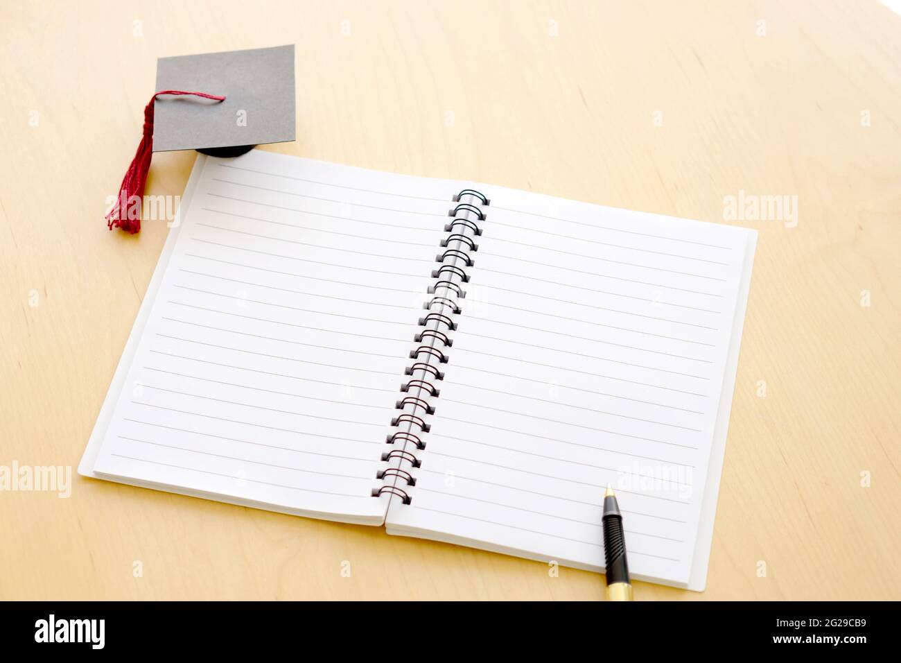Blank notebook on the table and graduation cap Stock Photo - Alamy