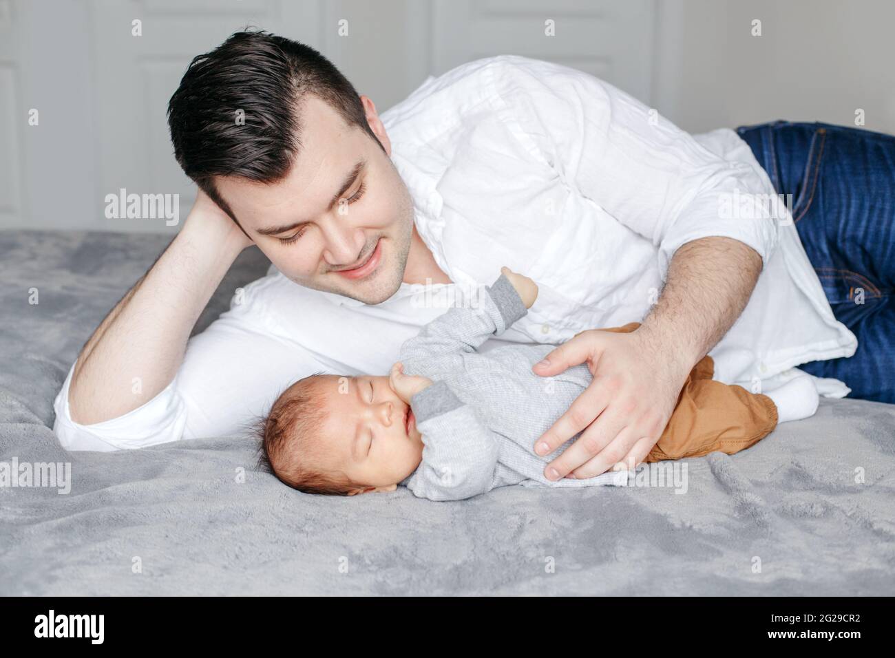Fathers day holiday. Happy proud dad hugging newborn baby boy at home ...