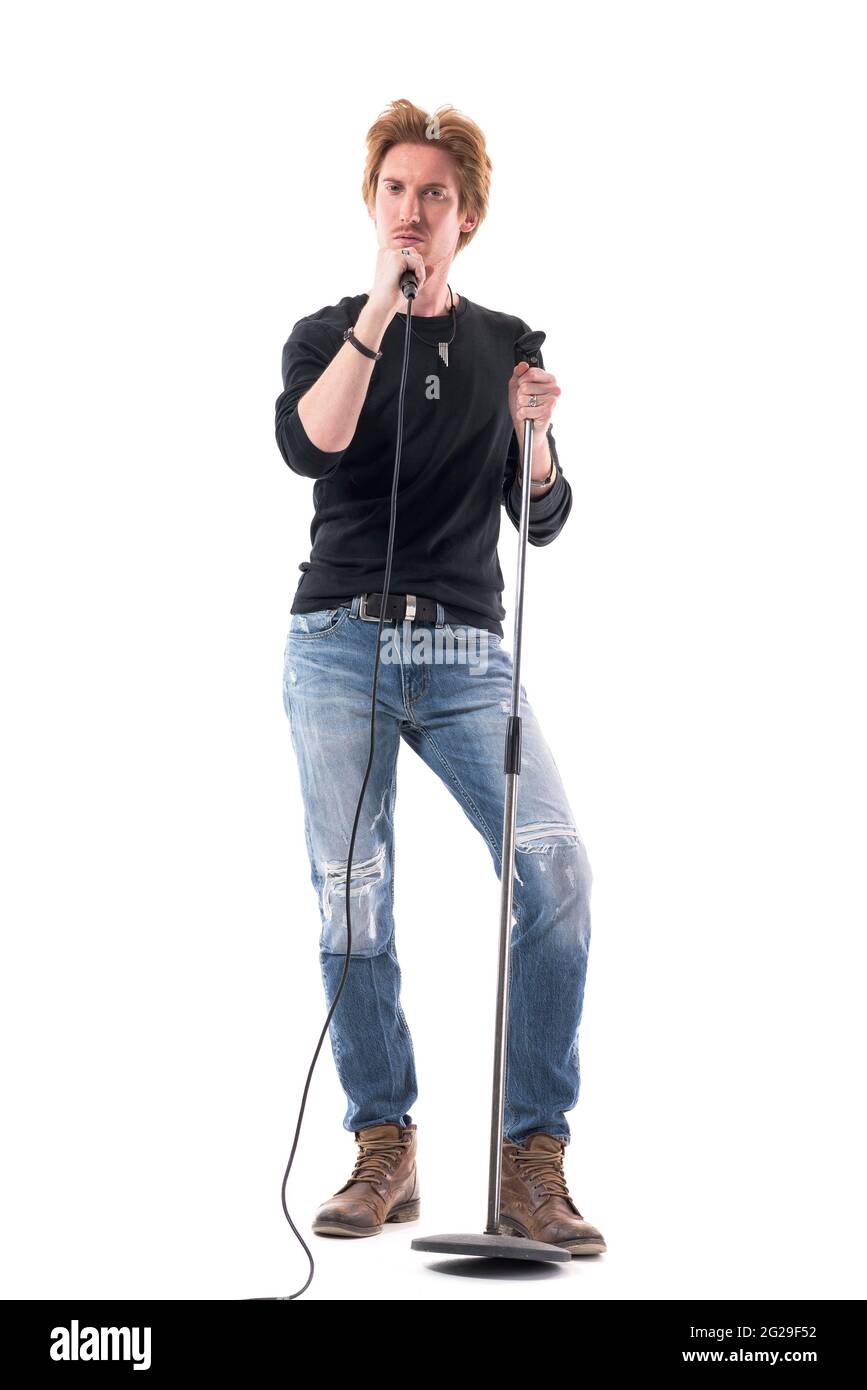 Handsome confident rock music singer holding microphone looking at ...