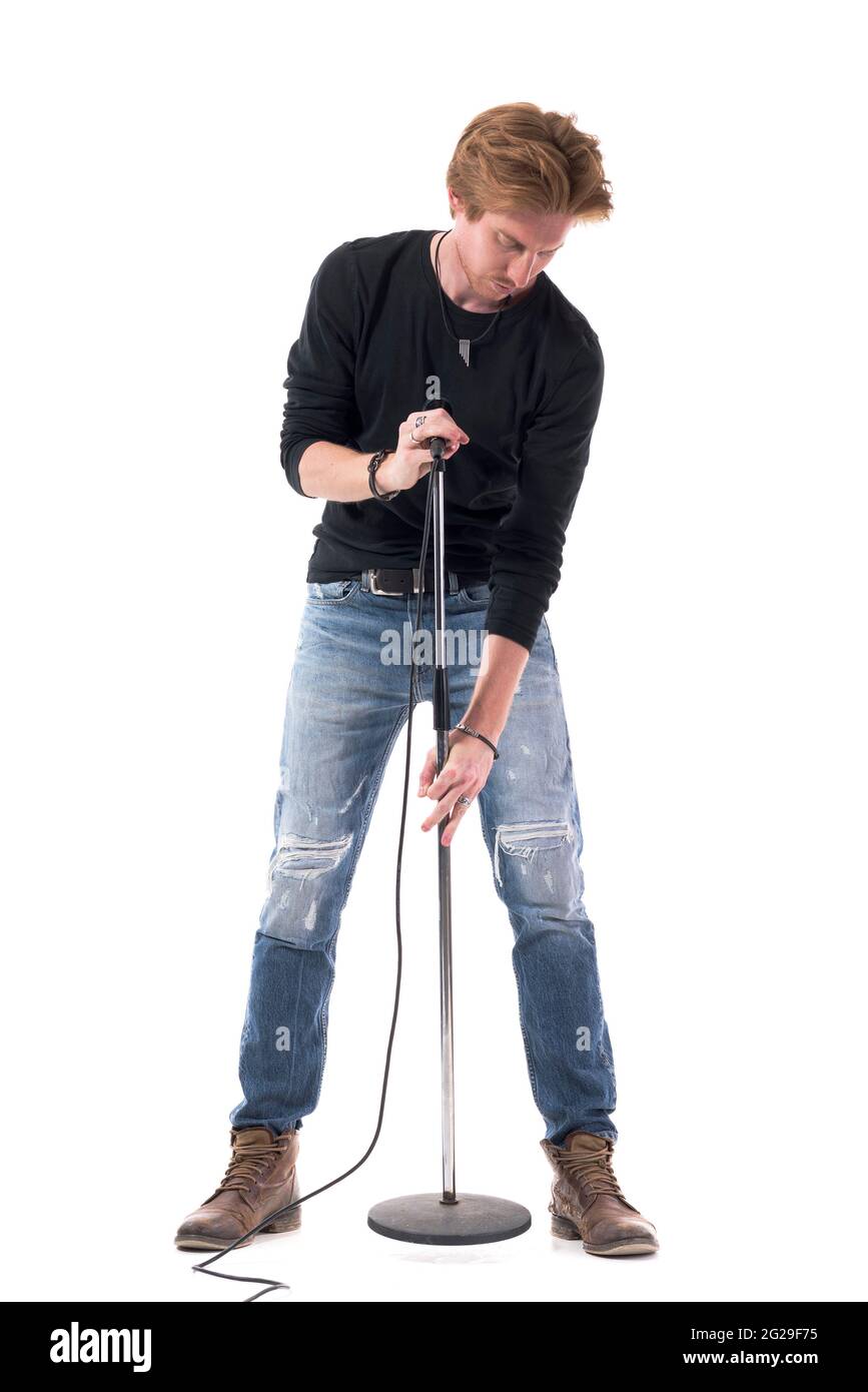 Young good-looking rock singer adjusting microphone stand height. Full ...