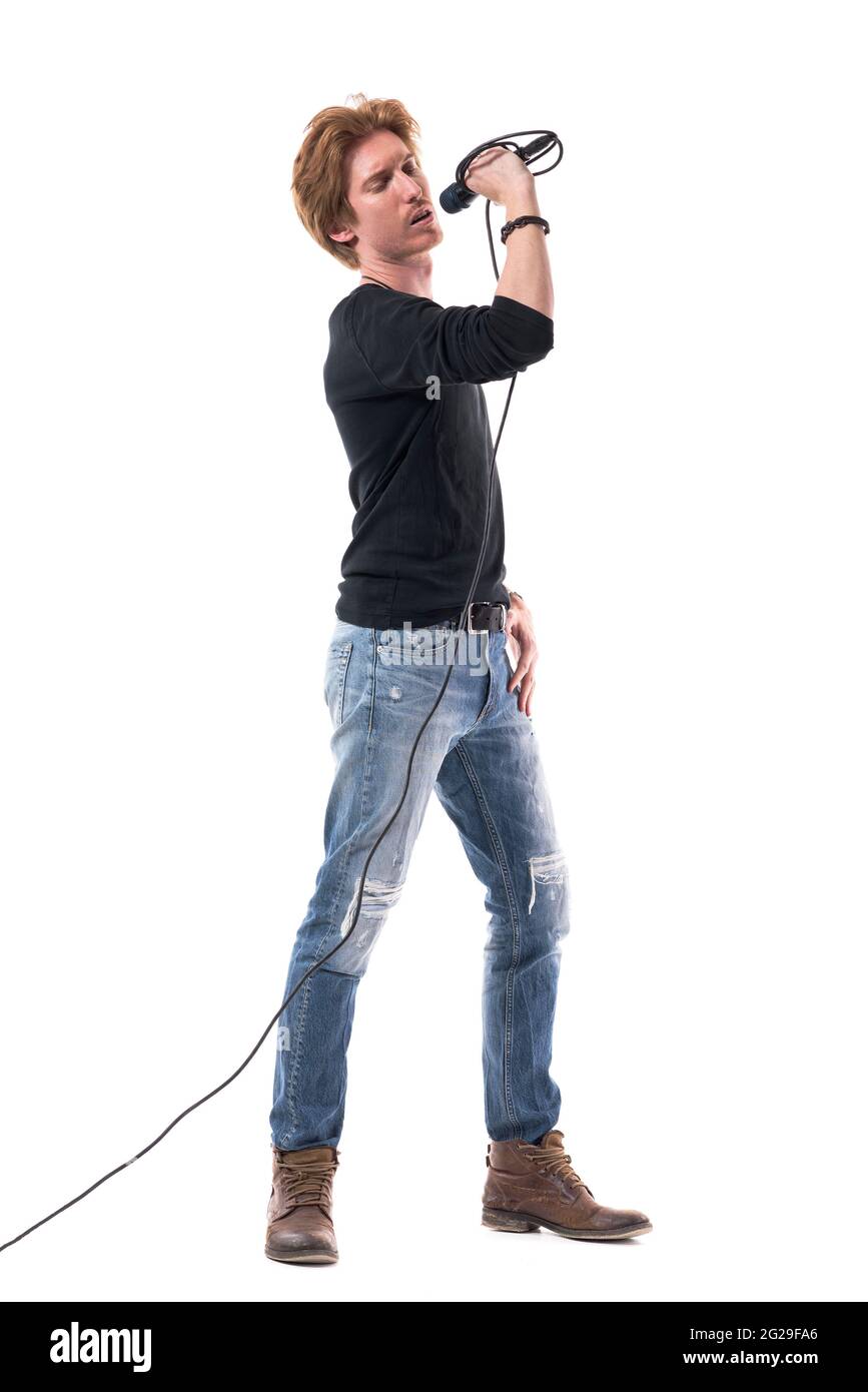 Handsome young stylish singer singing on microphone with closed eyes ...