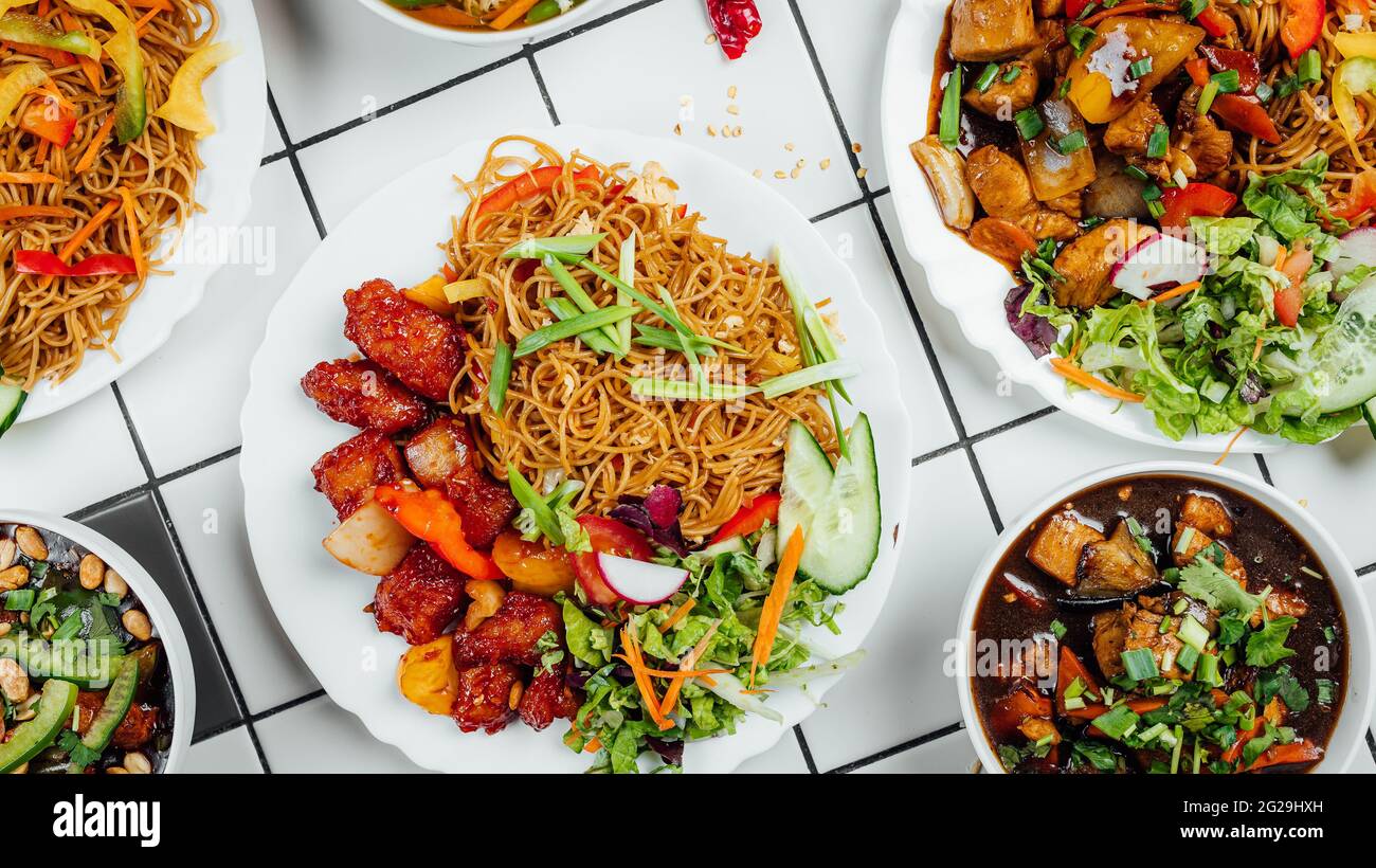 Top view of a variety of food including noodles, spicy chicken wings ...