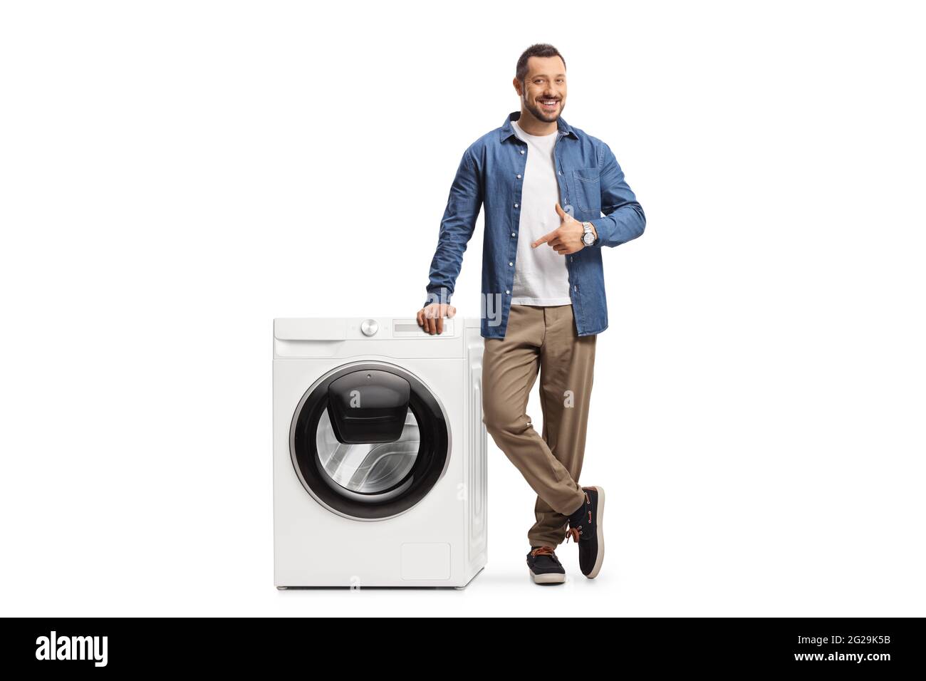 Young man leaning on a washing machine and pointing isolated on white ...
