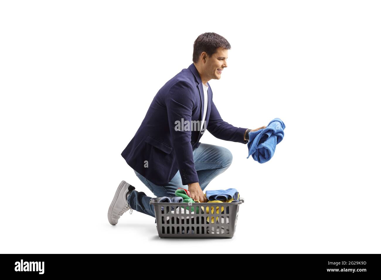 Man with a laundry basket kneeling and sorting clothes isolated on ...