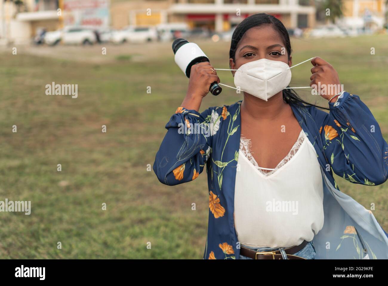 African journalist putting on face mask while on the street in the city ...