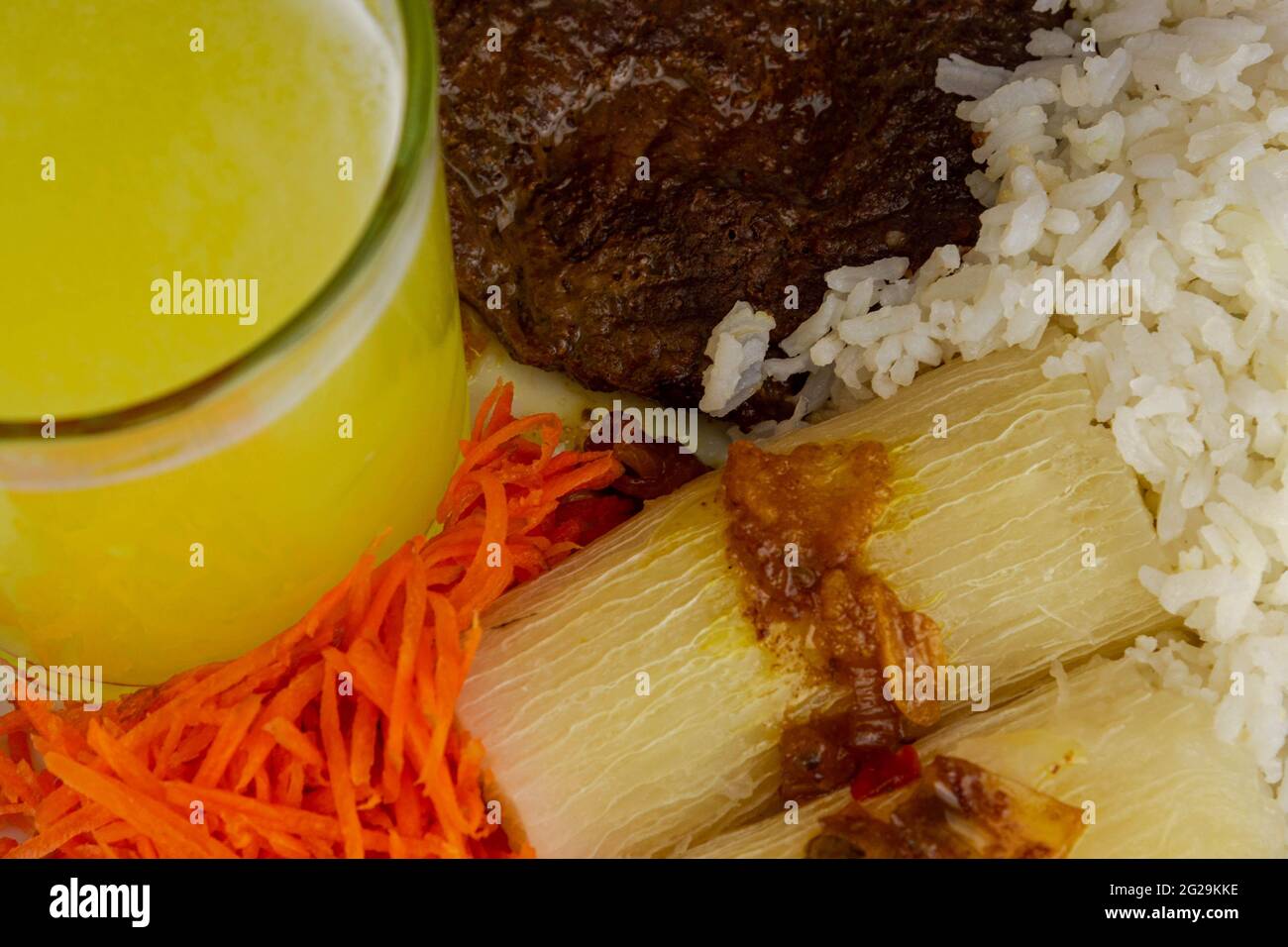 Brazilian food dish with steak and rice and carrots and cassava with an ...