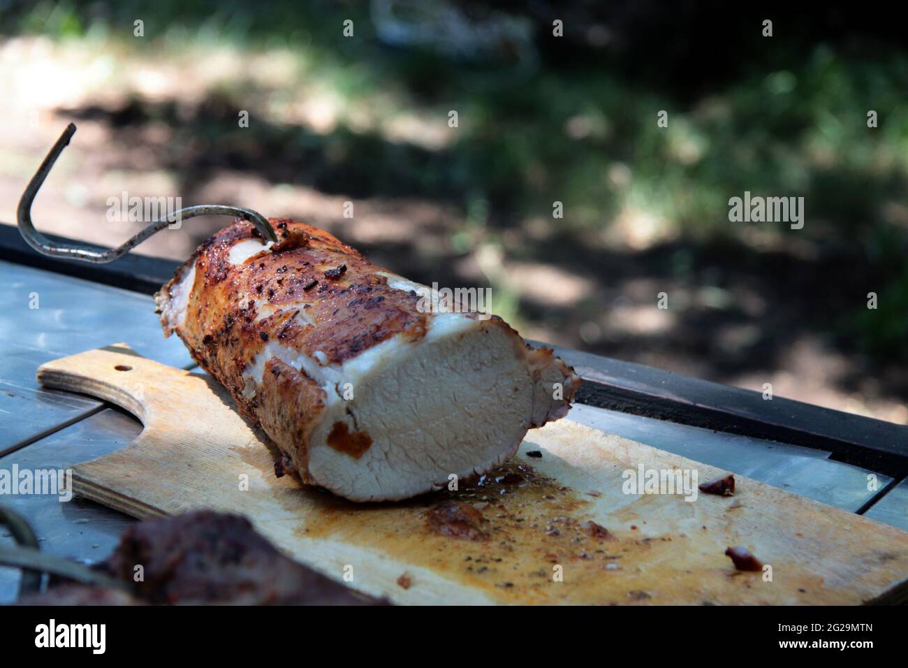 slab of meat on a cutting board on a BBQ party in the park Stock Photo ...