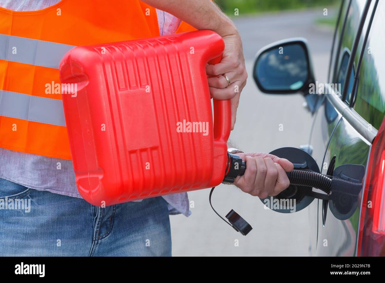 Driver fills the fuel in an empty car tank from red canister on the ...