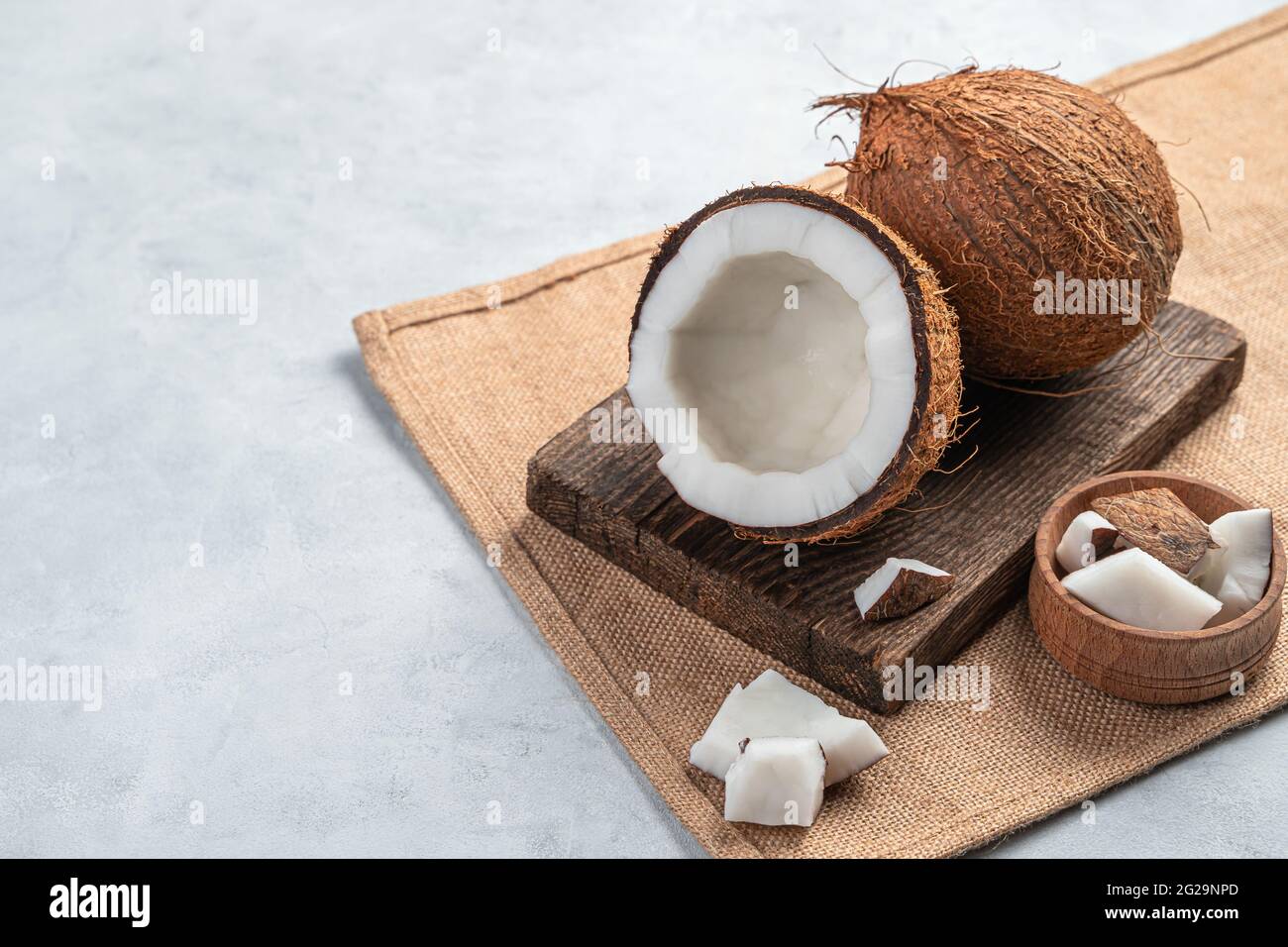 A whole and open coconut with pieces on a gray background. Side view ...