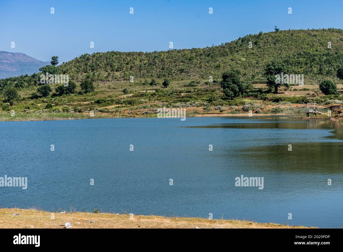 Awesome view of a small lake with a fishing boat near a greenery ...