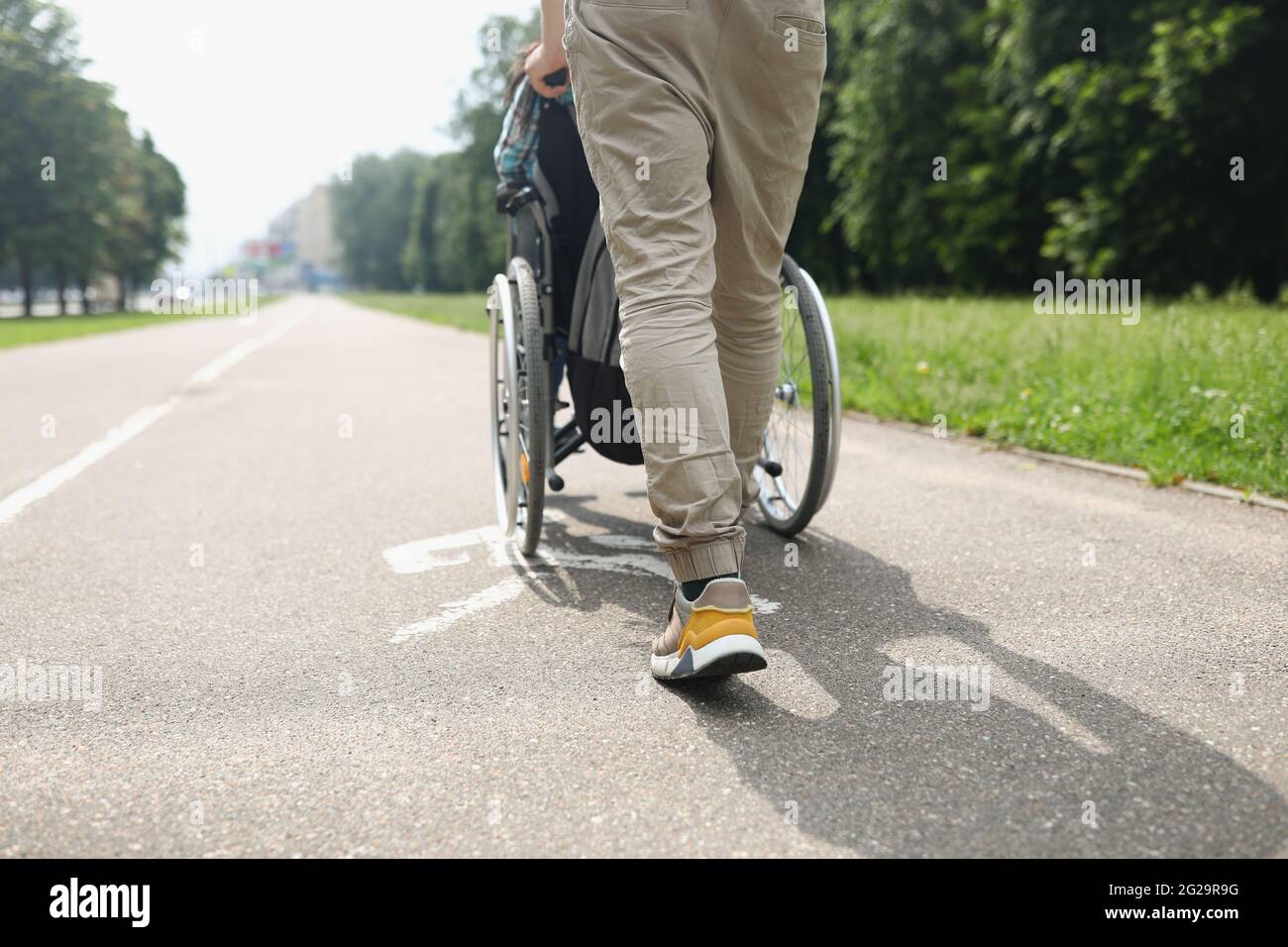 Man rolling wheelchair with disabled person on sidewalk closeup Stock ...