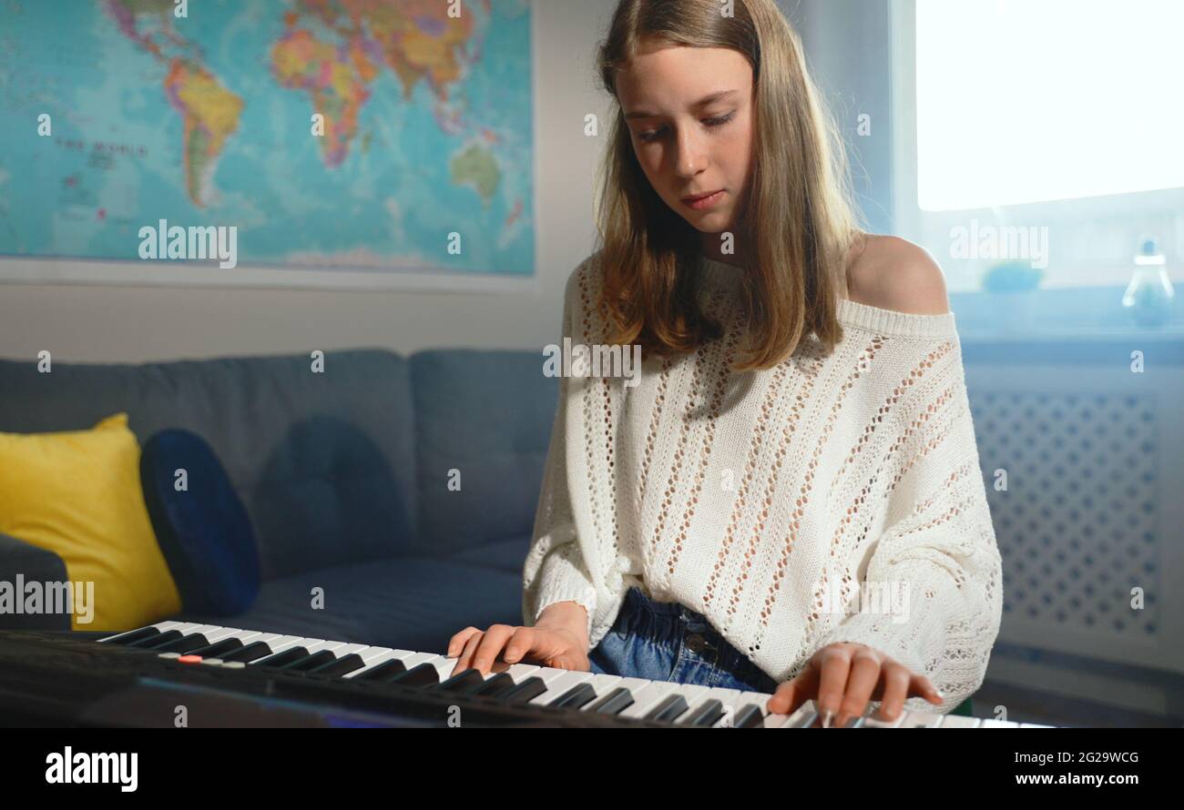 Teenage girl playing electronic musical instrument at home Stock Photo ...
