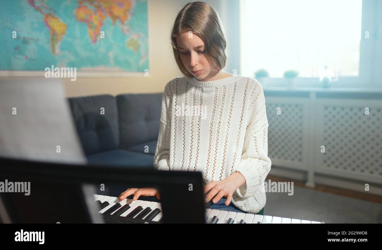 Teenage girl playing electronic musical instrument at home Stock Photo ...