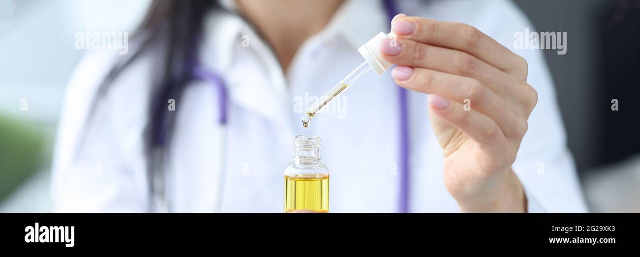 Doctor holds bottle with yellow liquid and pipette Stock Photo - Alamy