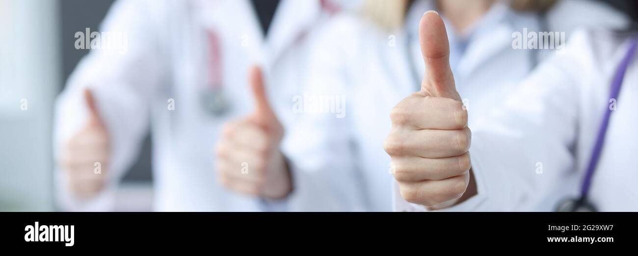 Three doctors stand behind each other and hold their thumbs up Stock ...