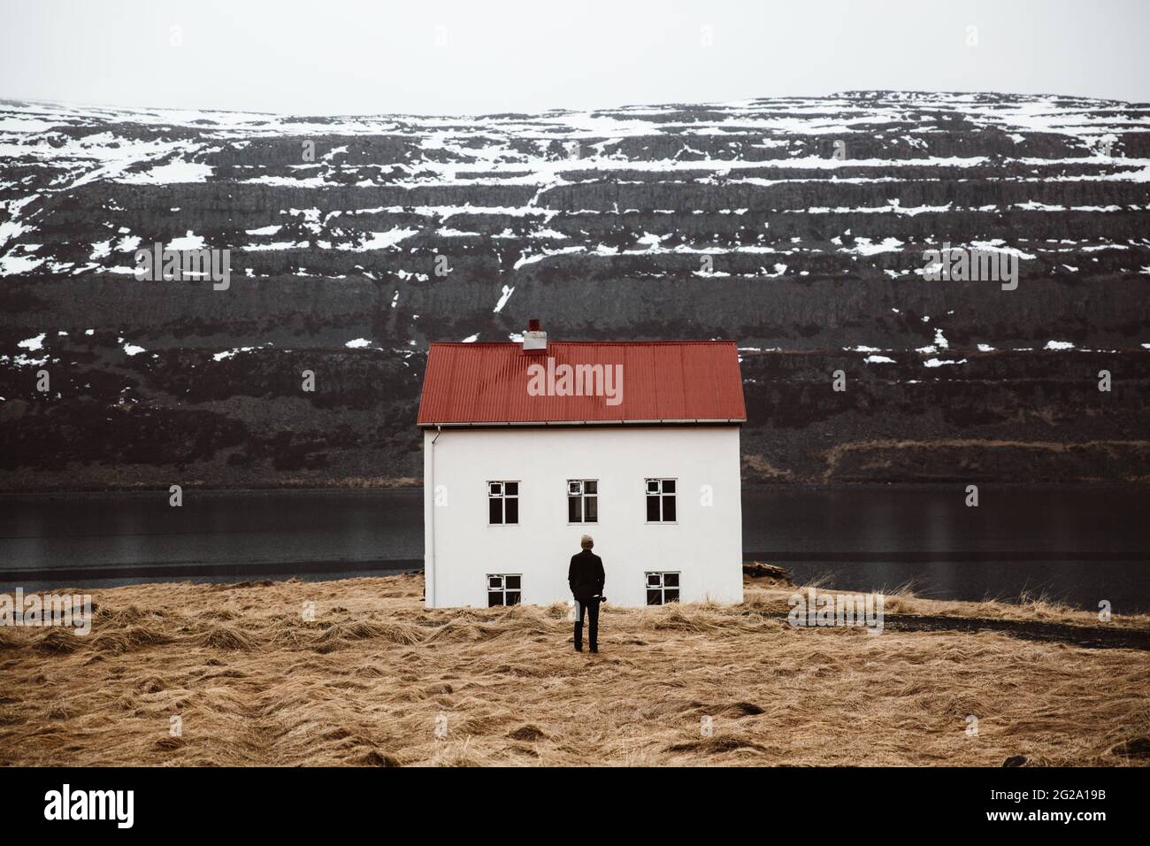 Traveler against house on cold shore Stock Photo - Alamy