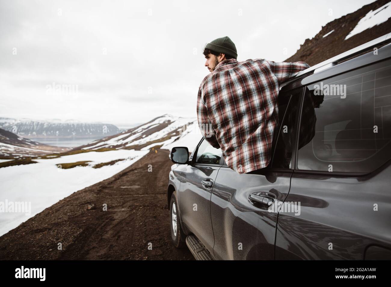 View of man looking out of car window looking away on snowy highlands ...
