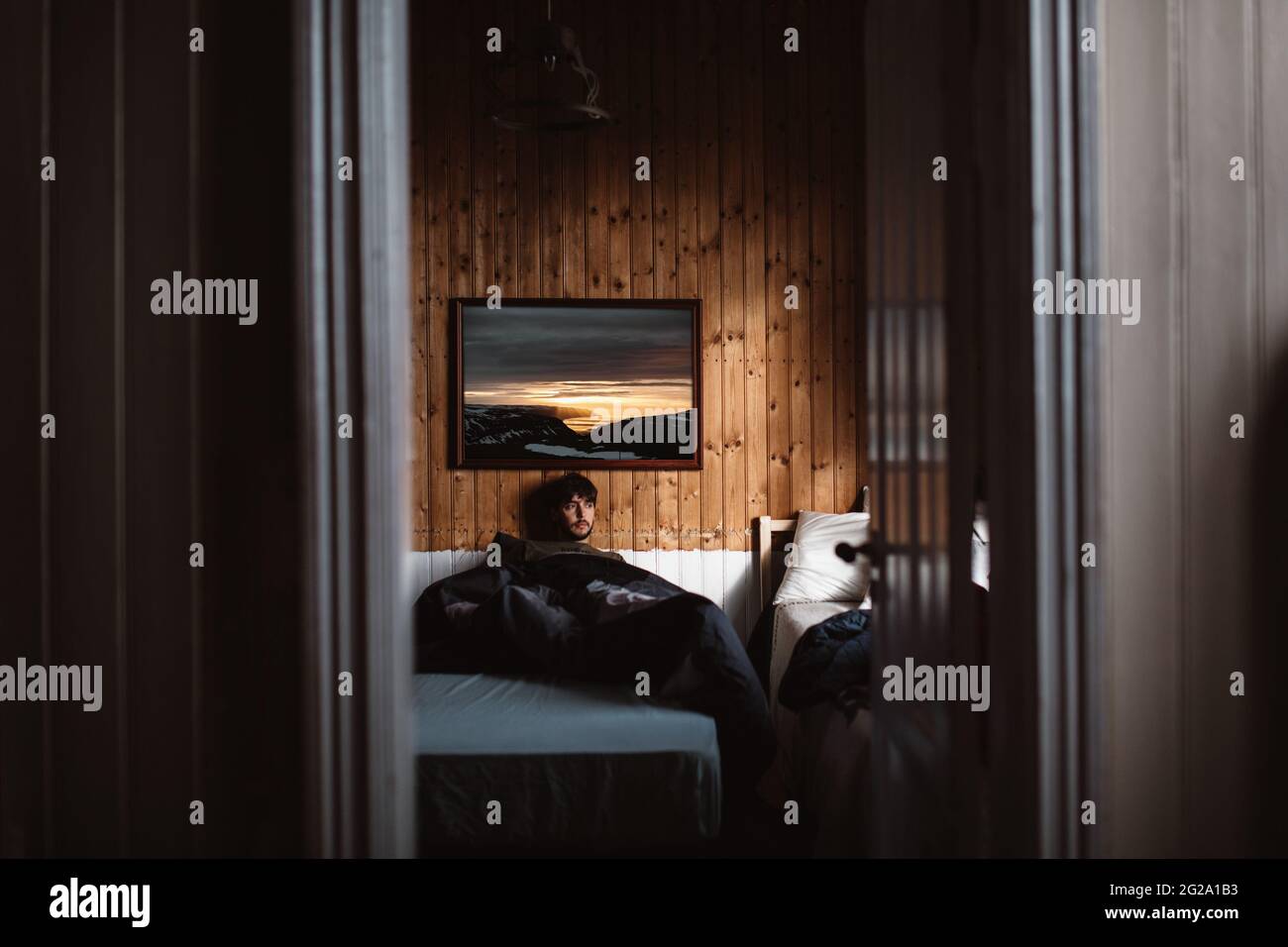 Dreaming man in bedroom looking away Stock Photo - Alamy