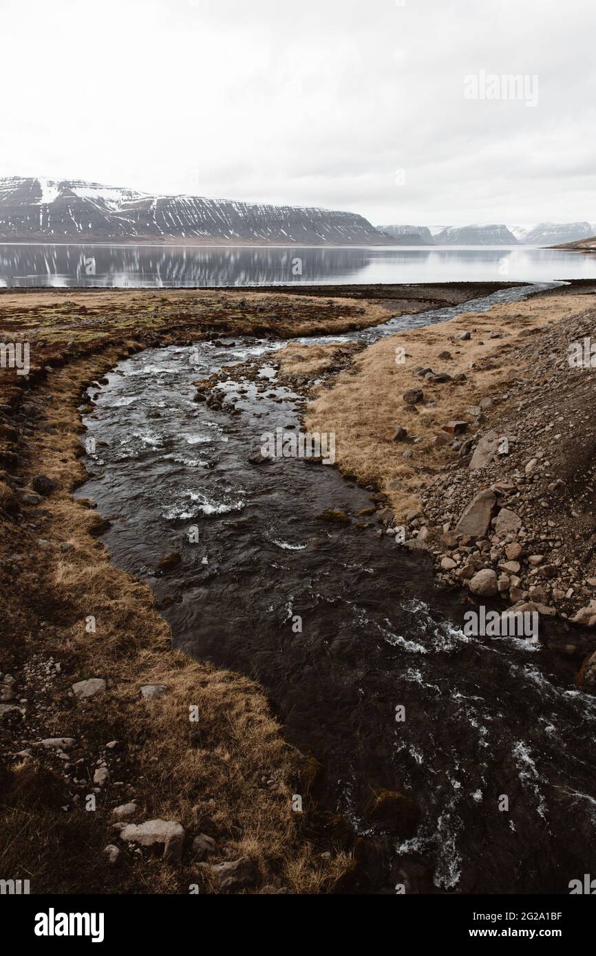 View of splashing clear water of stream flowing into tranquil lake with ...