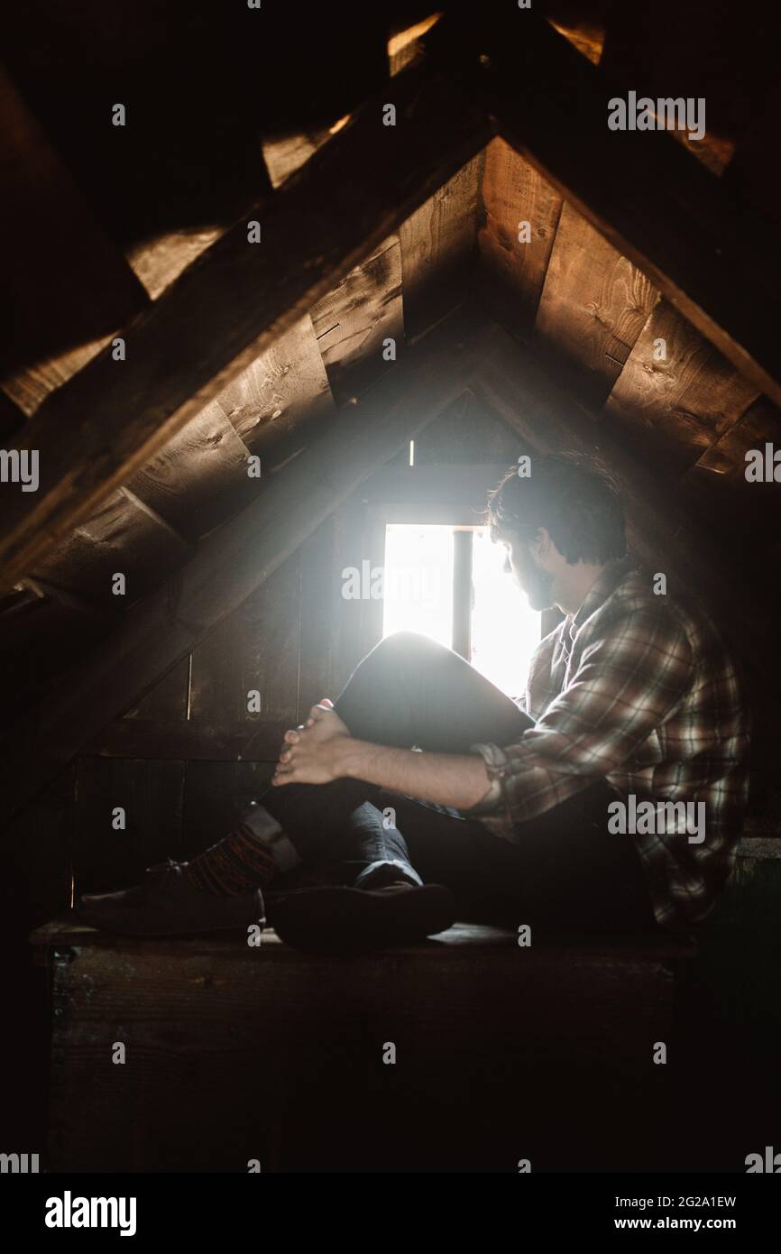 Anonymous man looking out window in attic Stock Photo - Alamy