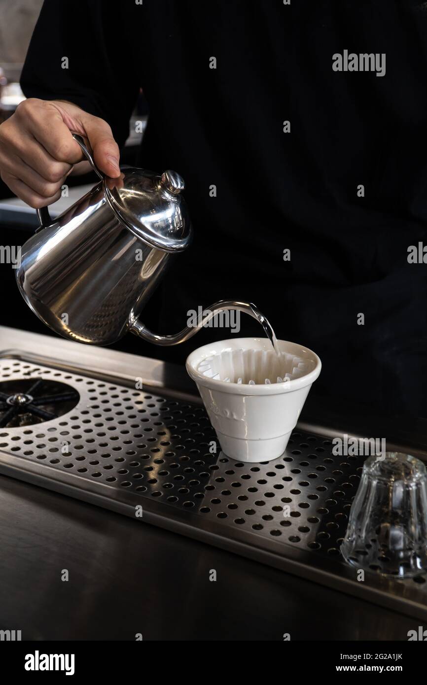 Cropped unrecognizable hand making coffee old style pouring hot water ...