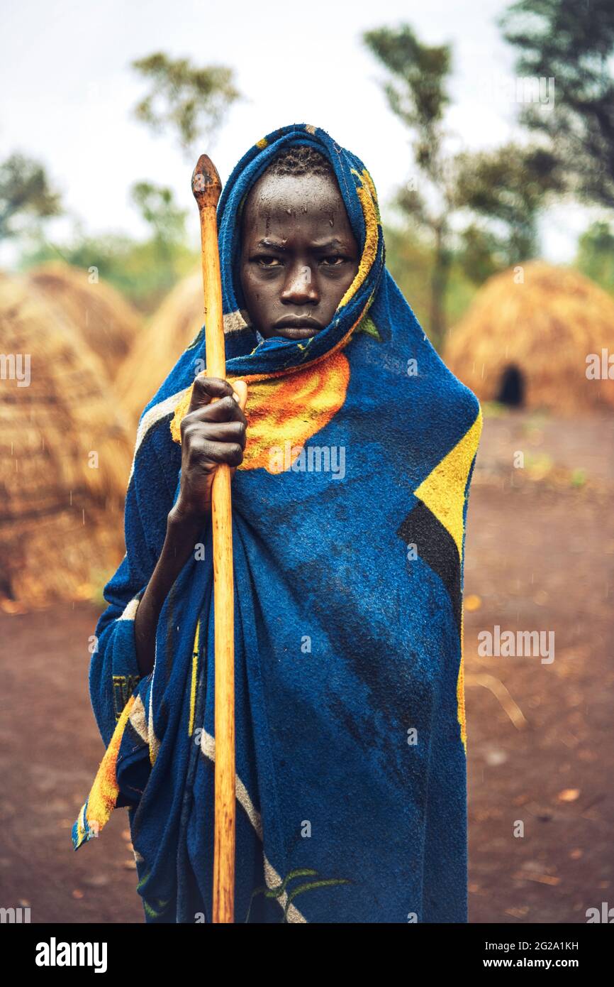Teen boy holding wooden spear and wrapping in bright apparel while ...