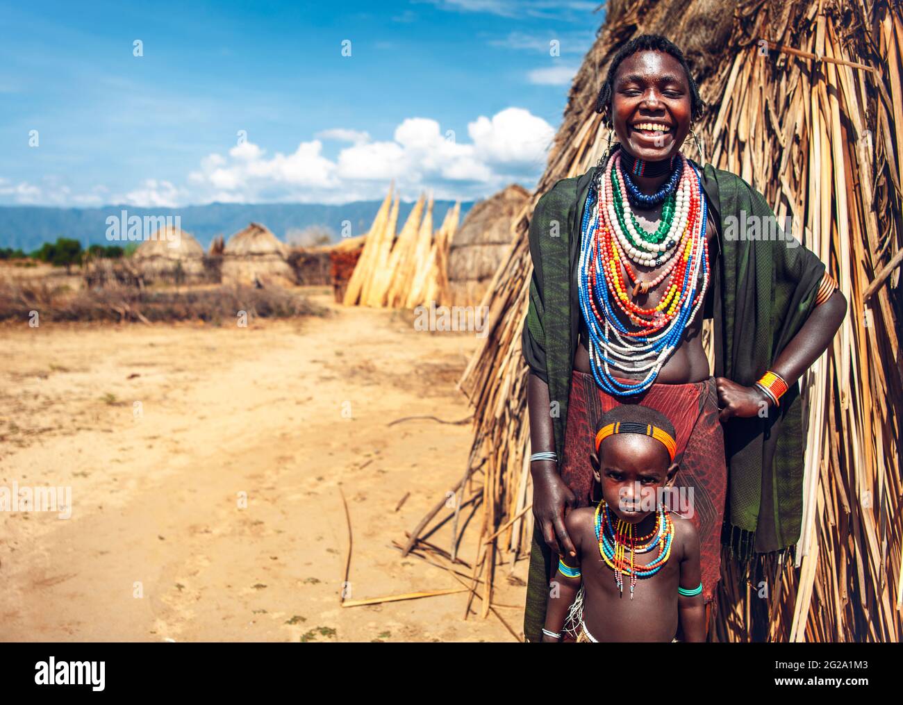 Woman in traditional clothes smiling and with her boy in Arbore tribe ...