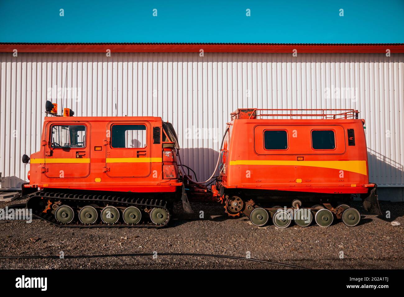 Modern red crawler vehicles on rocky road with white construction and ...