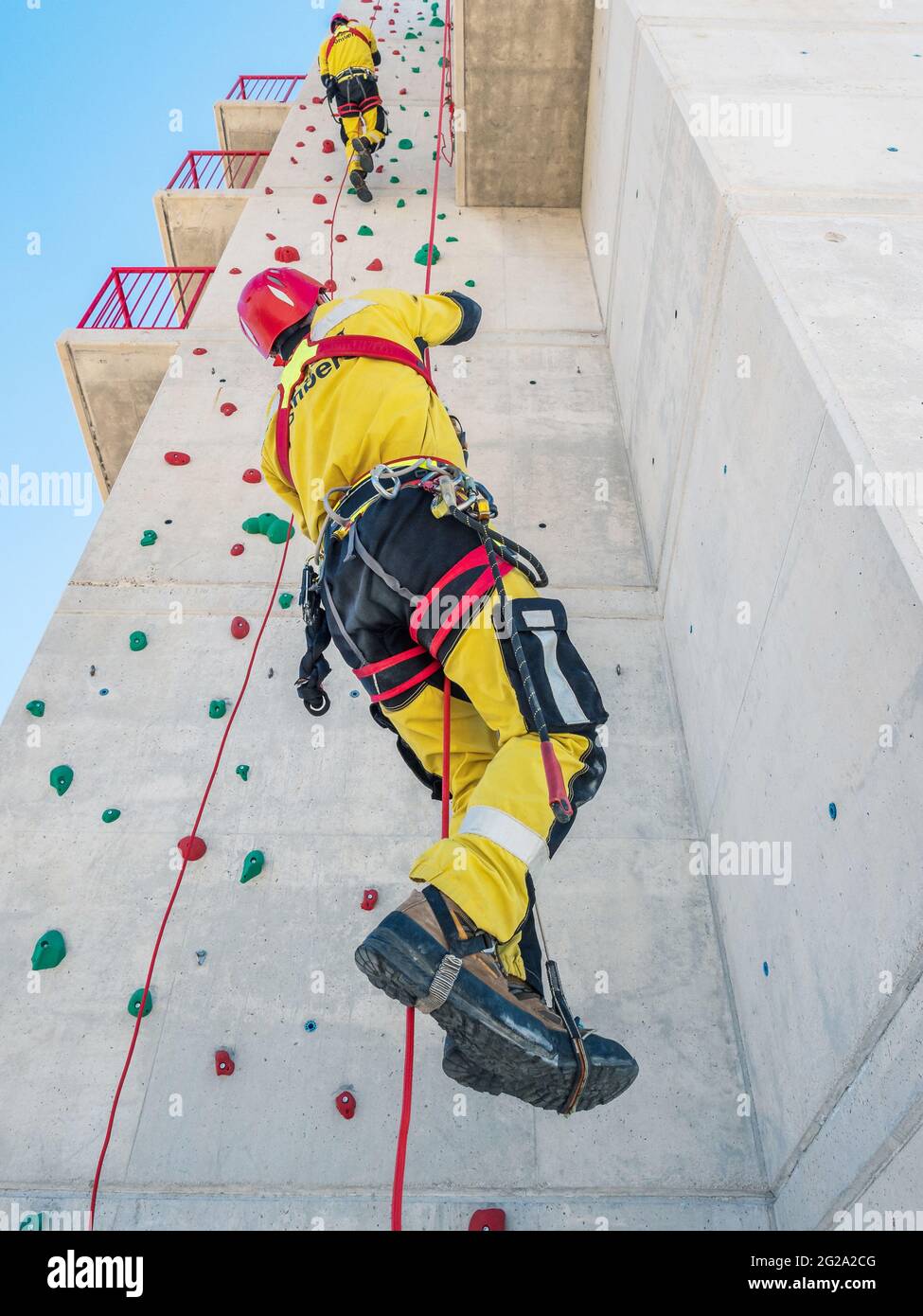 Professional firemen climbers in uniform hanging on ropes while ...