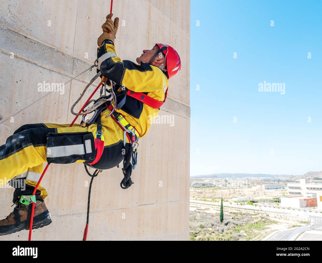 Professional fireman climber in uniform hanging on ropes while training ...
