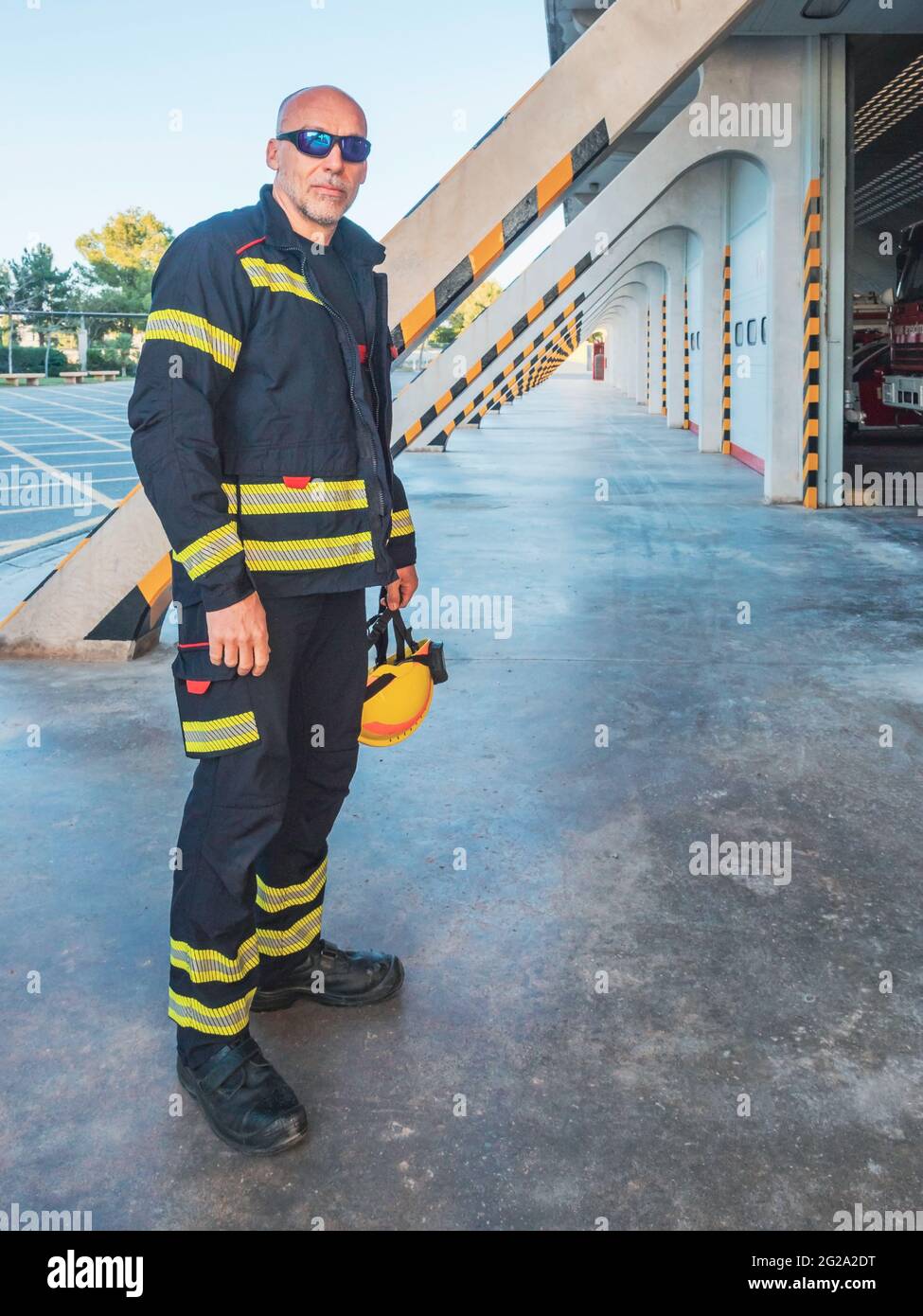 Professional fireman standing near fire truck and looking at camera ...