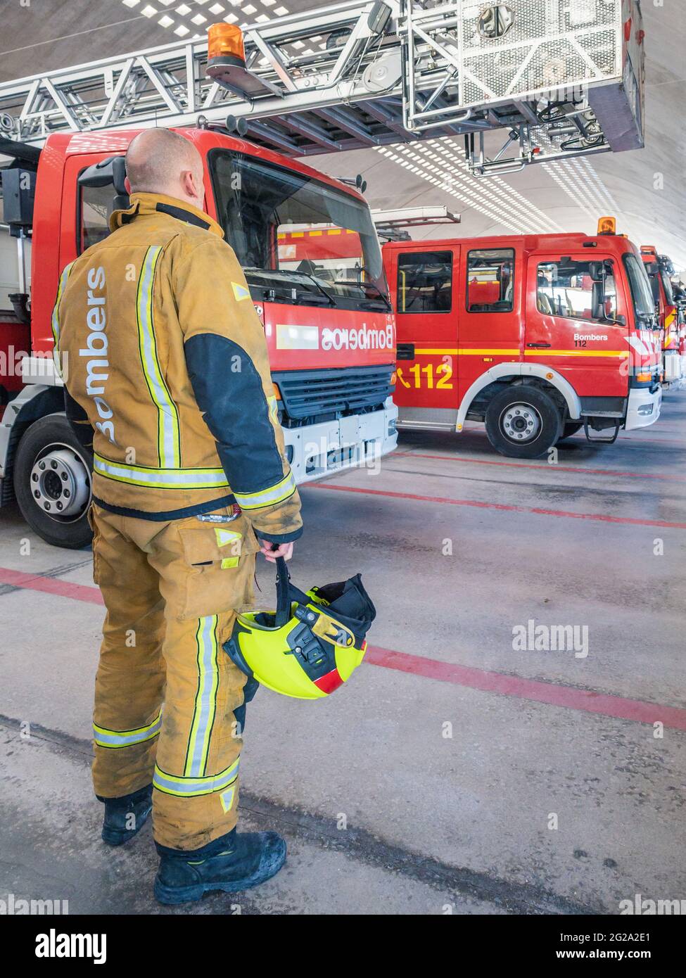 Back view of Fireman standing in fire department looking at fire trucks ...