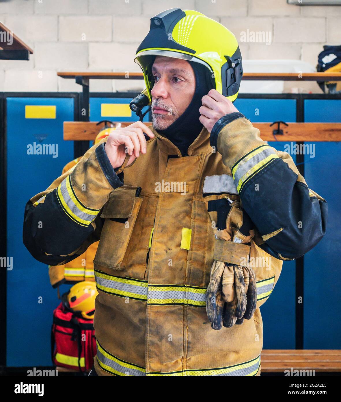 Fireman changing clothes and fastening his helmet in fire department ...