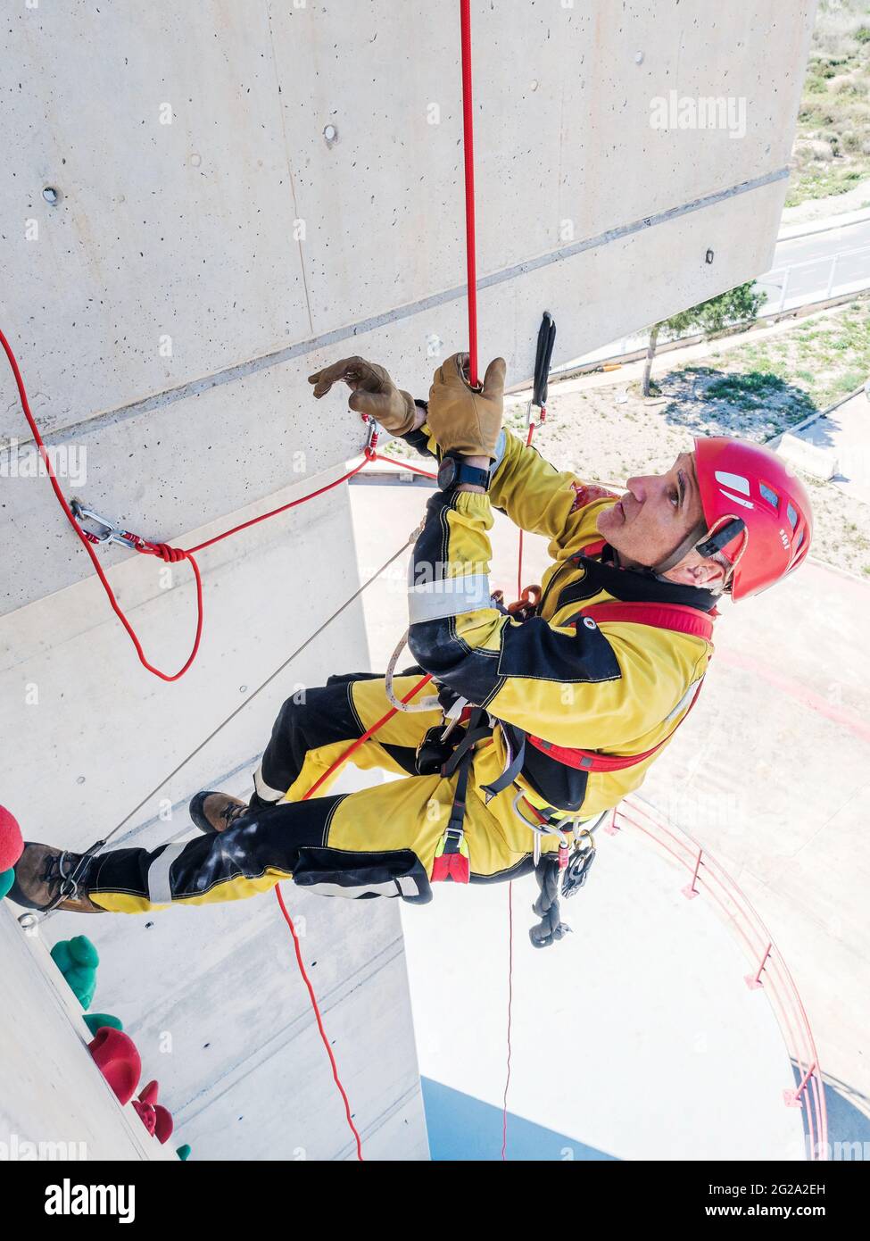Professional fireman climber in uniform hanging on ropes while training ...