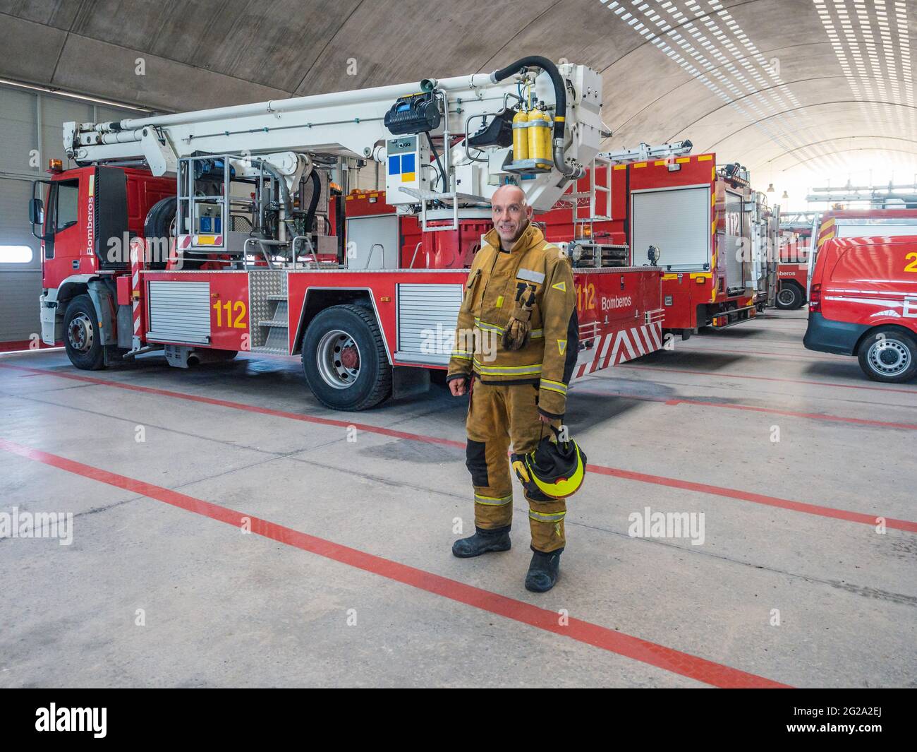 Professional fireman standing near fire truck and looking at camera ...