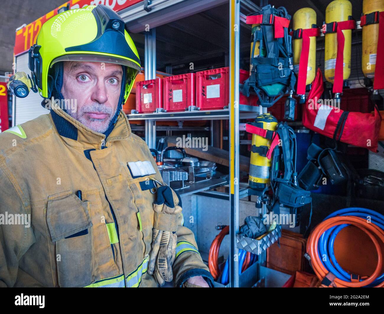 Professional fireman standing near fire truck and looking at camera ...