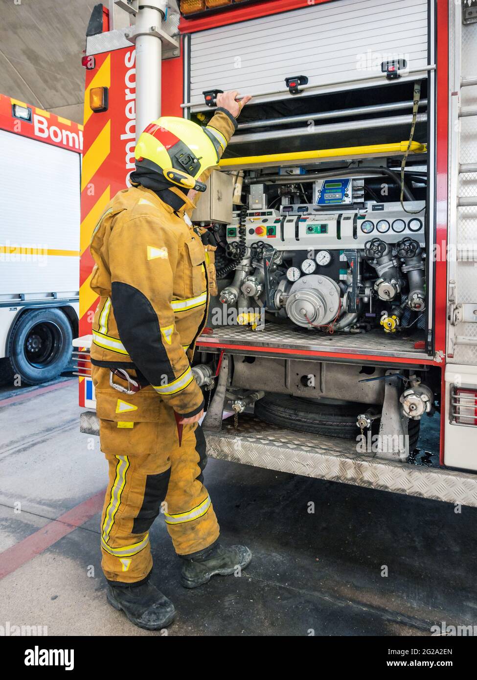 anonymous Equipped fireman standing and using an water engine into fire ...