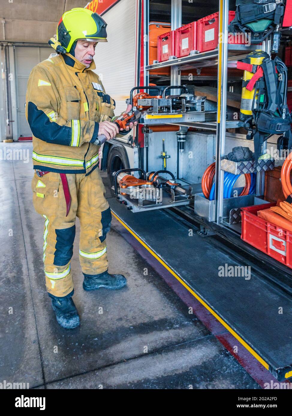 Professional fireman getting ready near fire truck and looking away ...