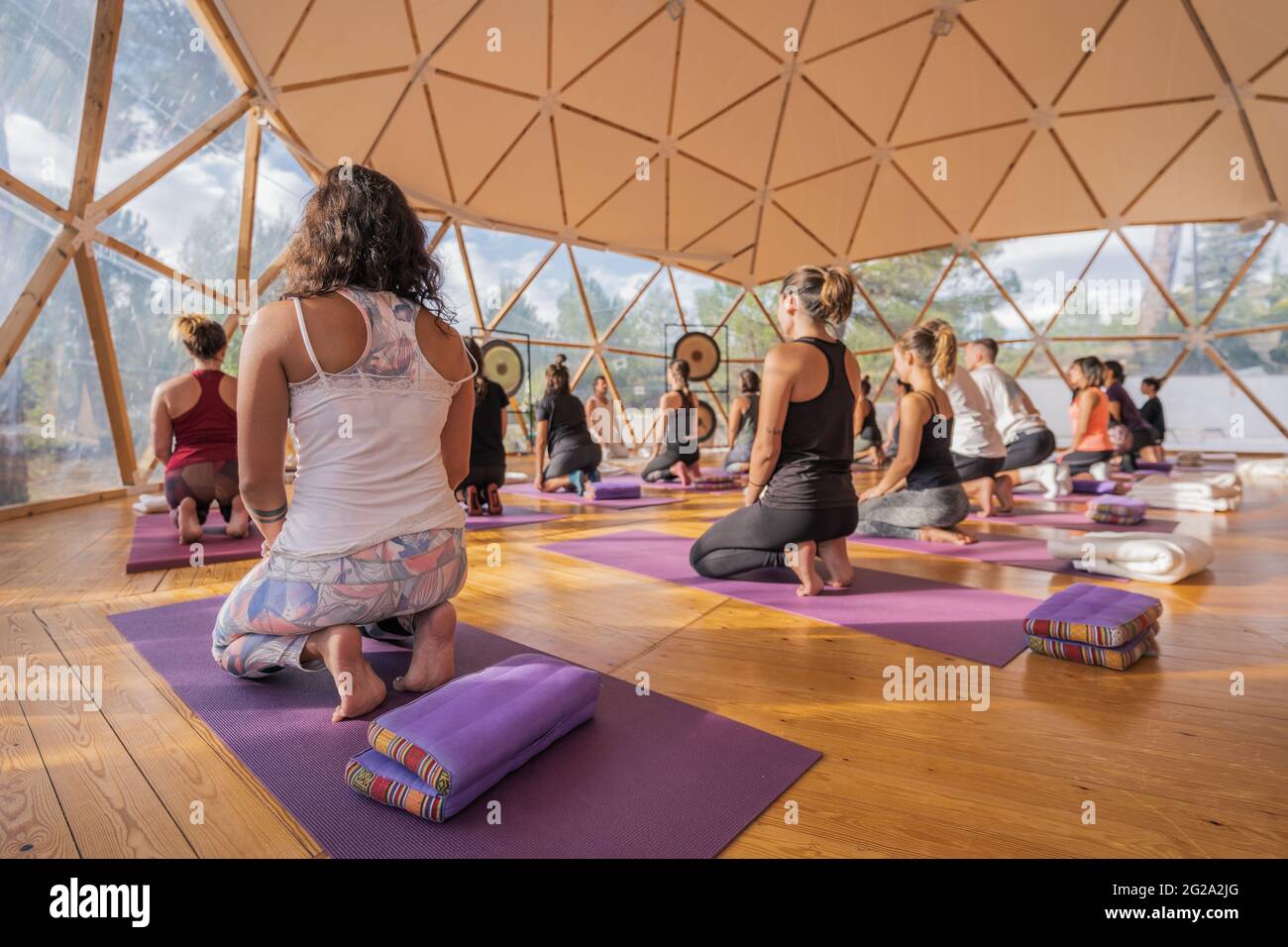 Back view of concentrated group of people sitting in lotus posture and meditating in round class ...