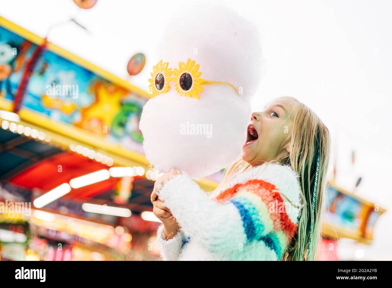 Little girl has fun at the fair with lights and eats sweet cotton Stock ...