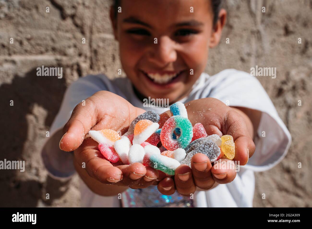 African child holding sweet jelly candies in hands while standing on ...
