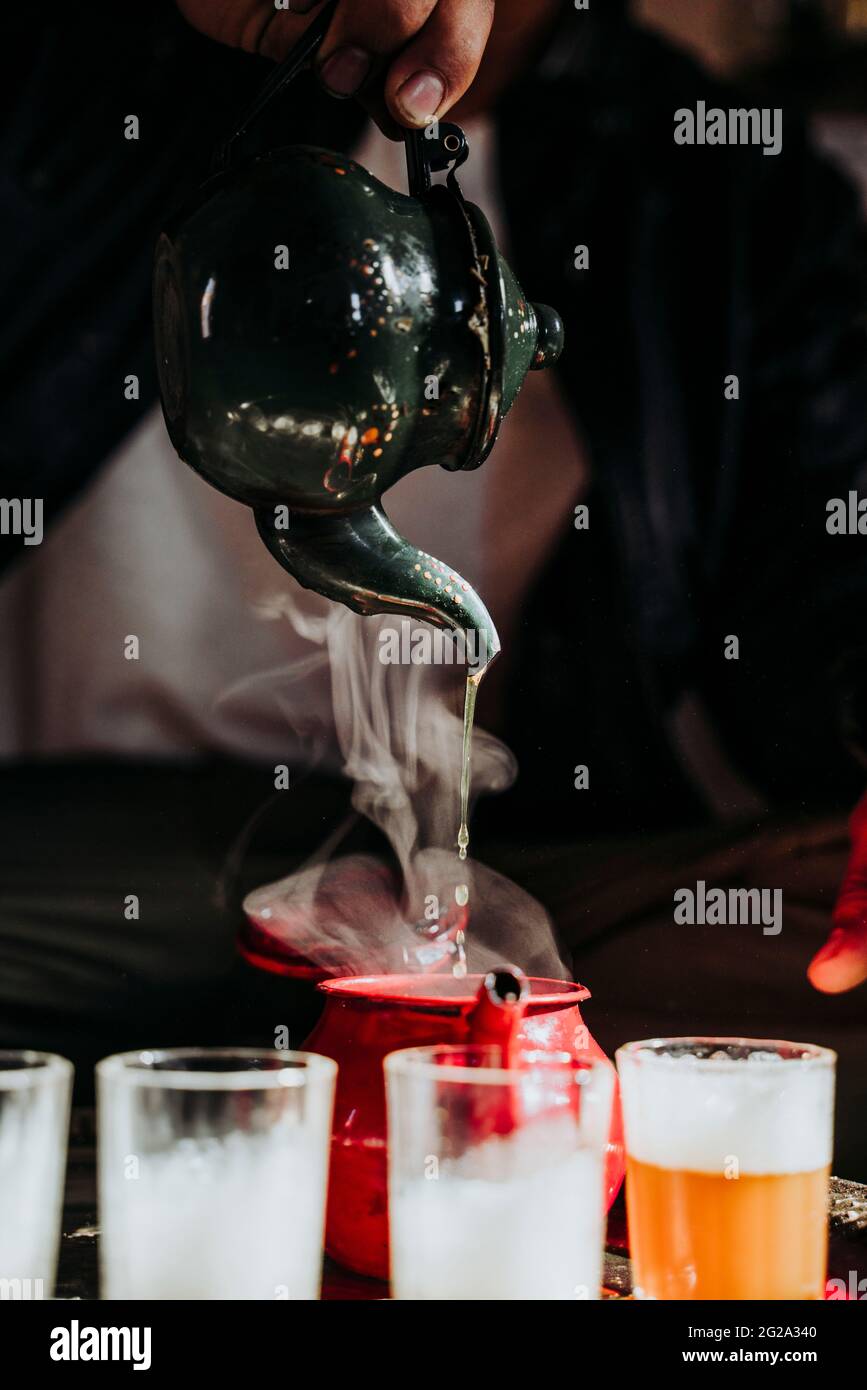 Unrecognizable black person pouring hot water in teapot while brewing ...