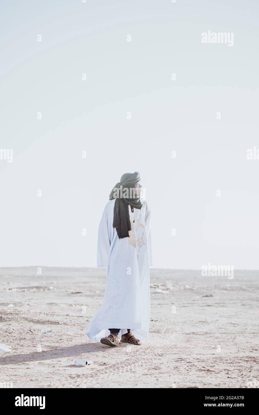 Side view of anonymous african male in traditional headgear and robe ...