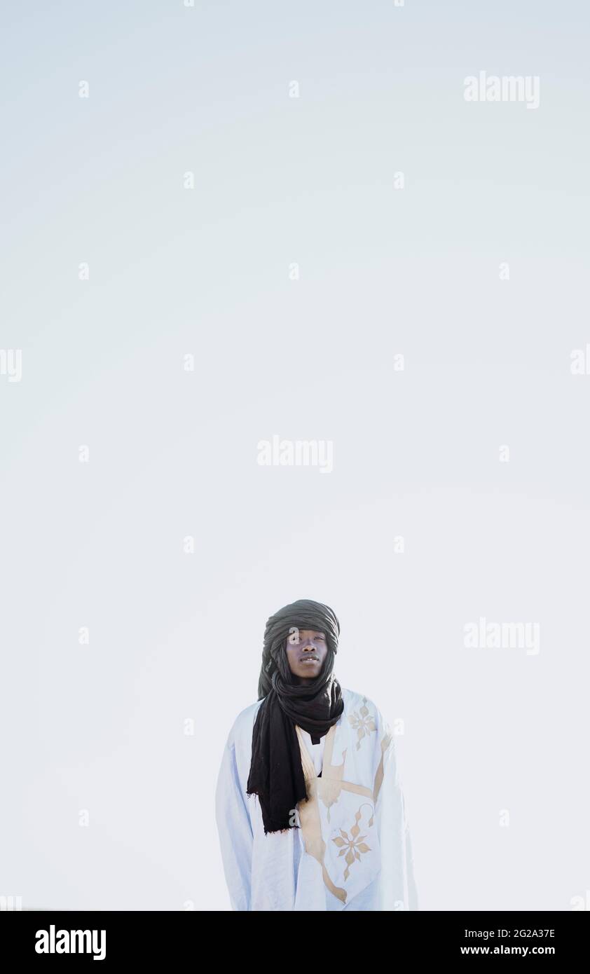 African male in traditional headgear and robe standing against ...
