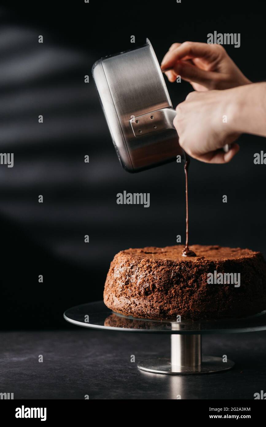 Side view of crop anonymous person with metal pan spilling chocolate ...
