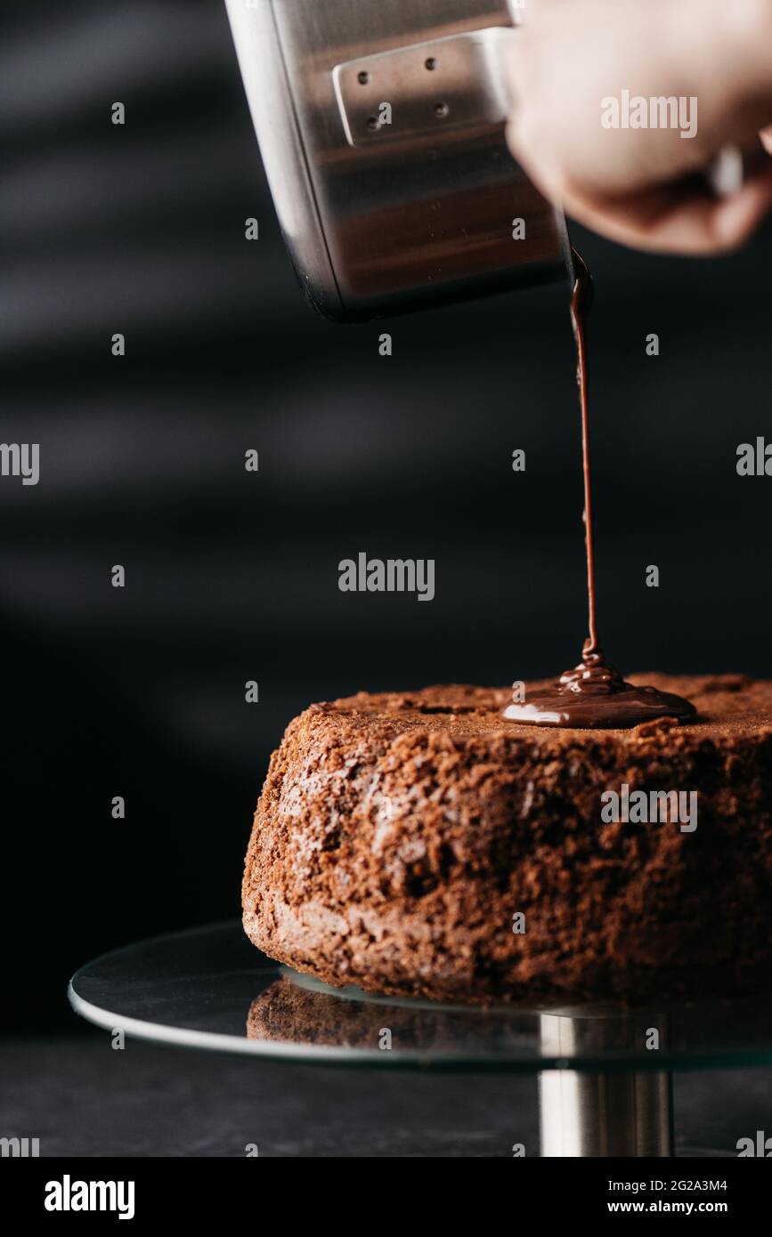 Side view of crop anonymous person with metal pan spilling chocolate ...