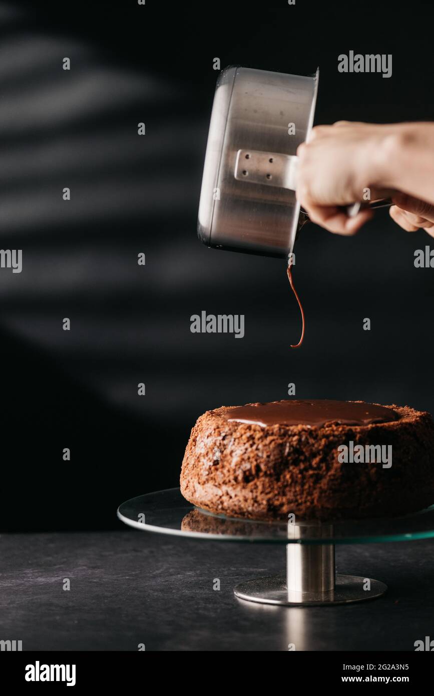 Side view of crop anonymous person with metal pan spilling chocolate ...