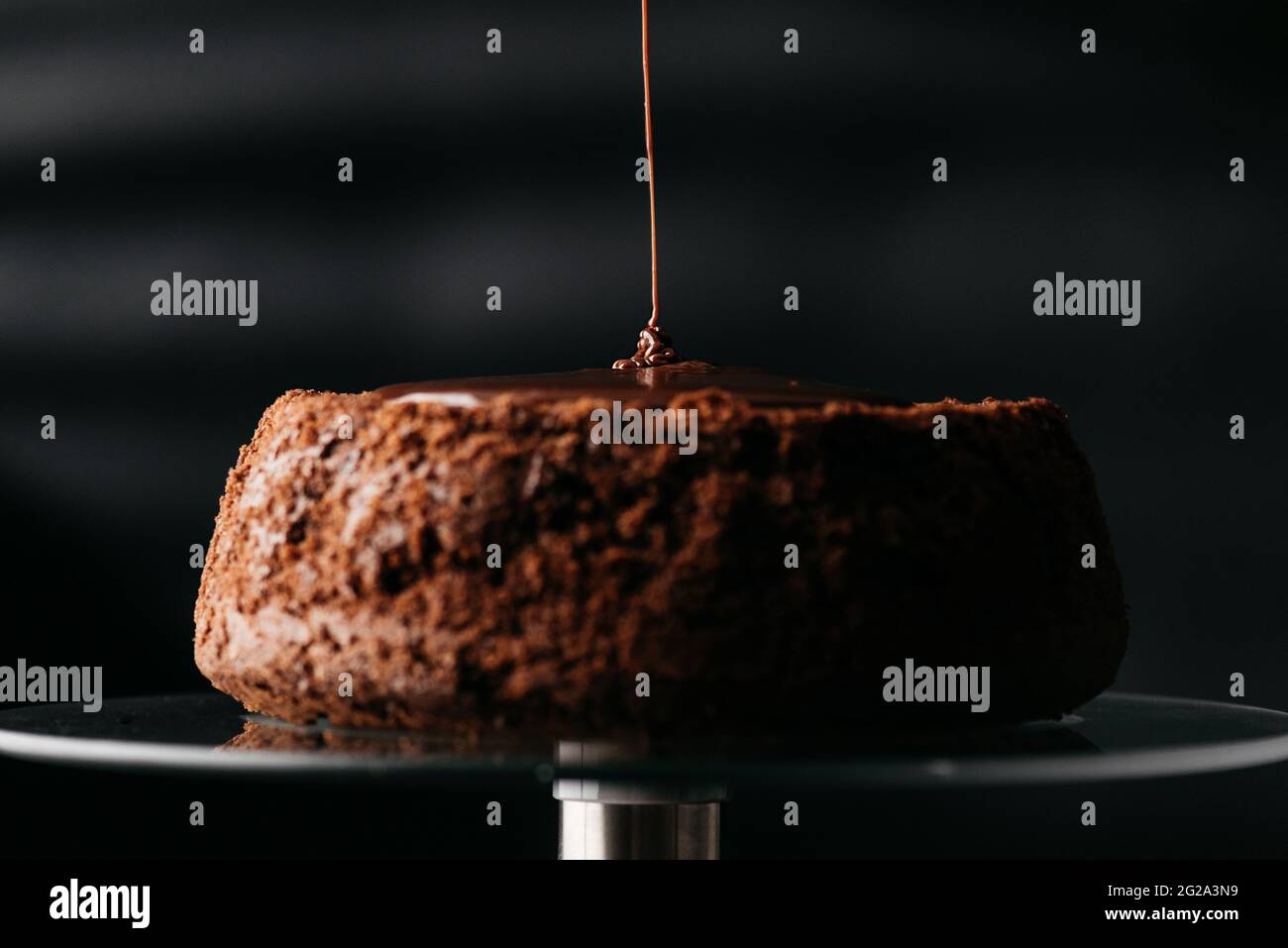 Spilling chocolate sauce falling on homemade cake placed on table ...