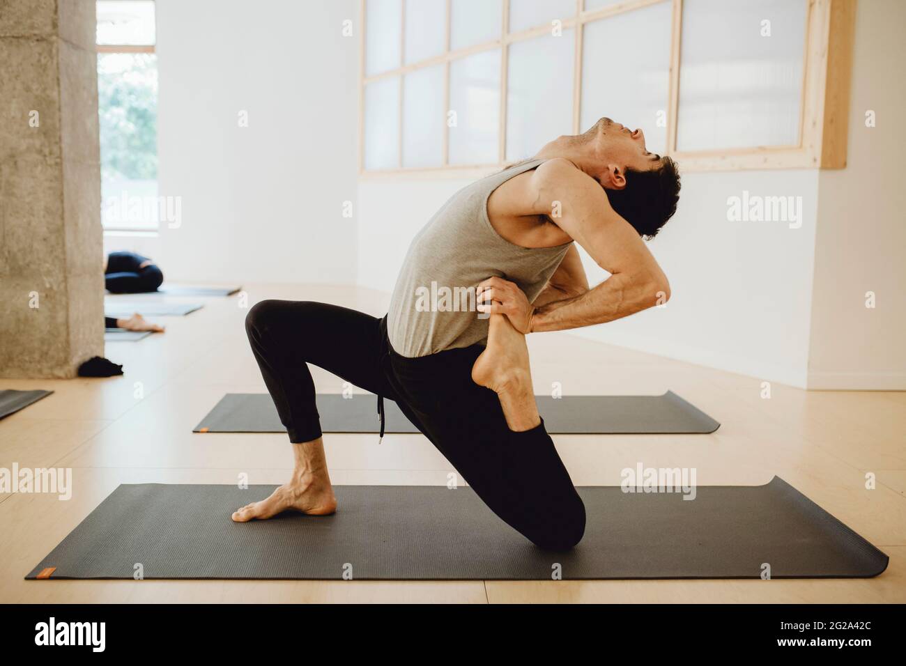 Side view of young slender man in sportive wear practicing yoga asana ...