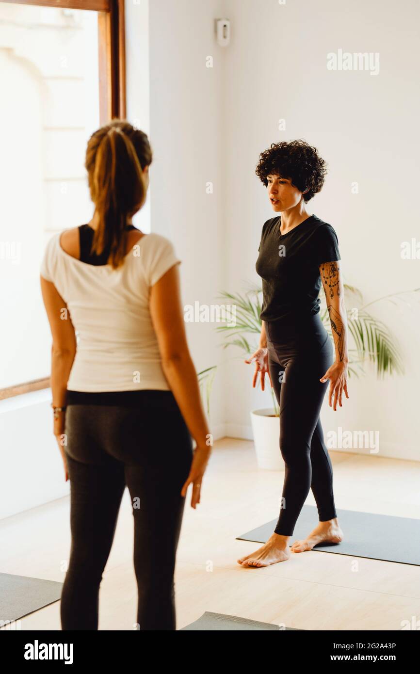 Attractive yoga teacher Woman showing young Woman a pose in training ...
